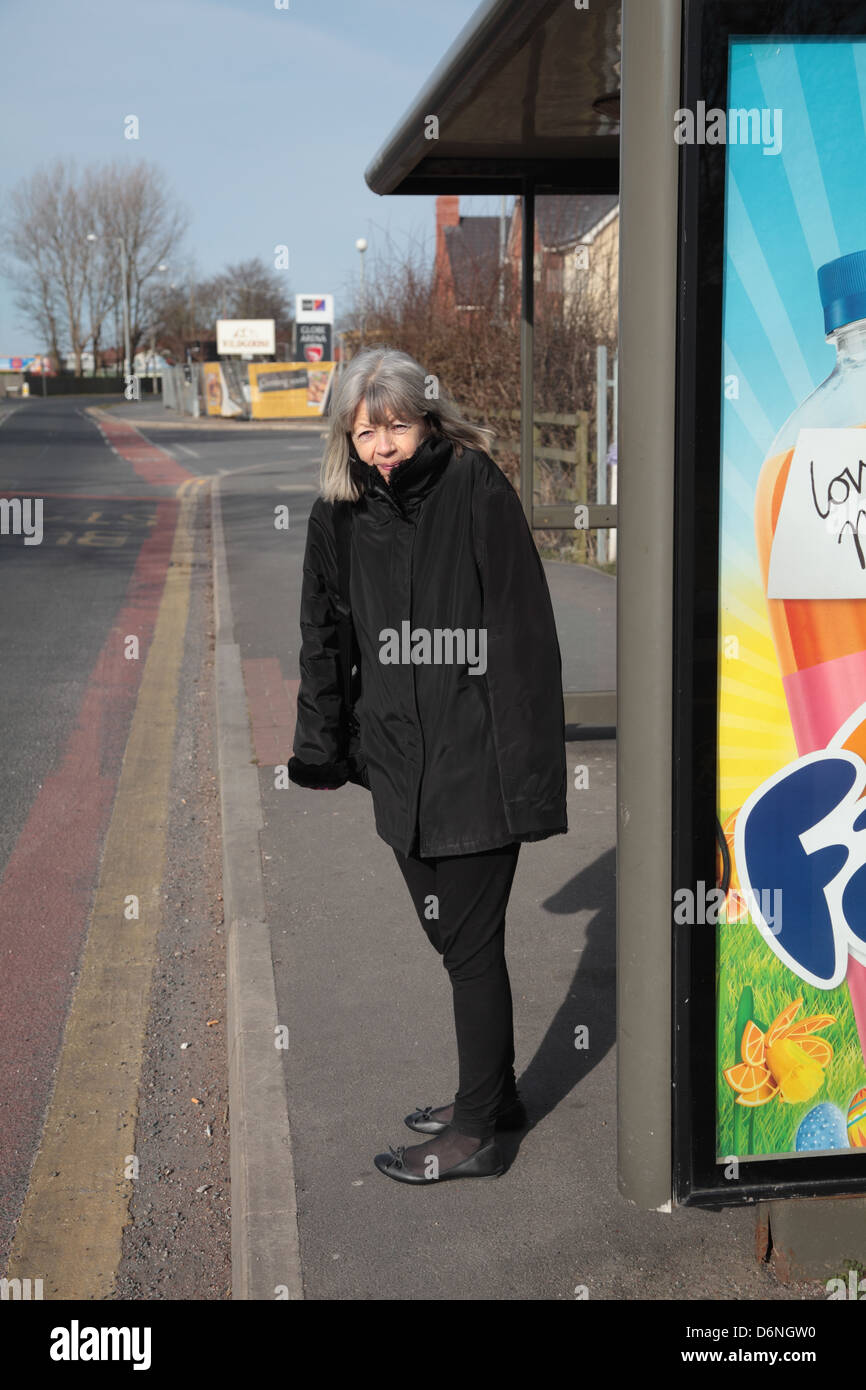 Woman standing at bus stop Stock Photo - Alamy