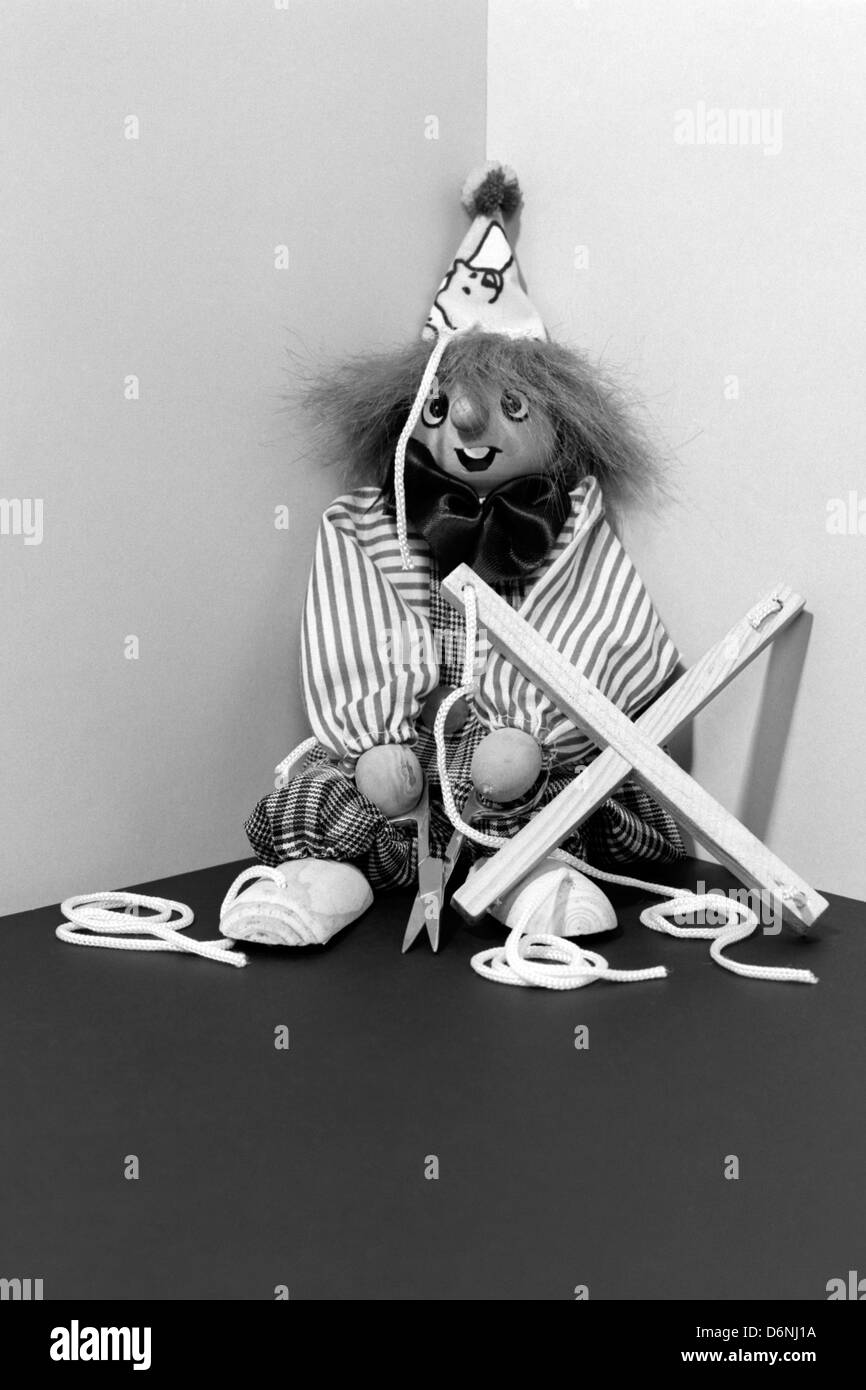 still life of puppet holding scissors with its control strings cut ...