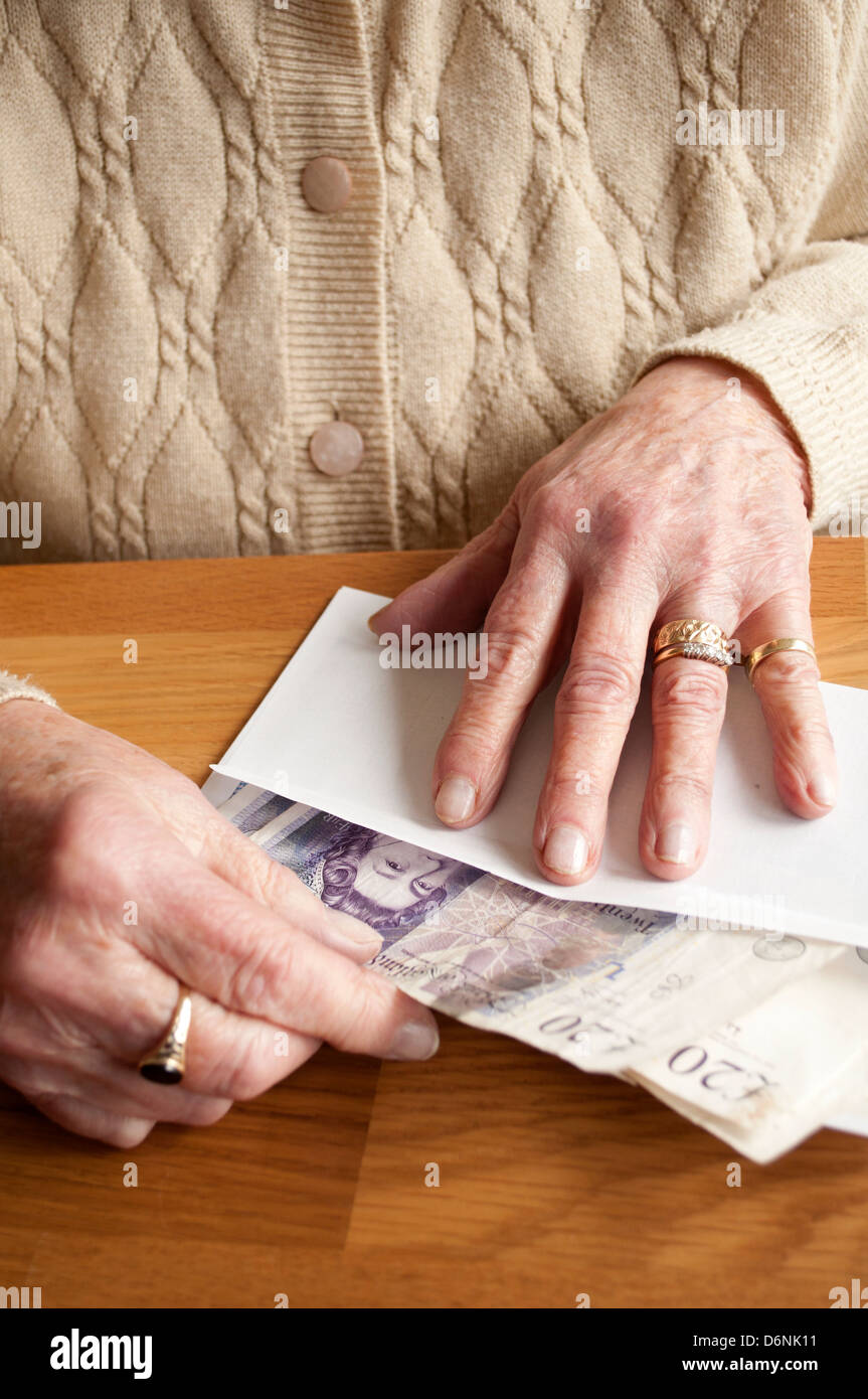 Elderly woman putting twenty pound notes into an envelope Stock Photo ...