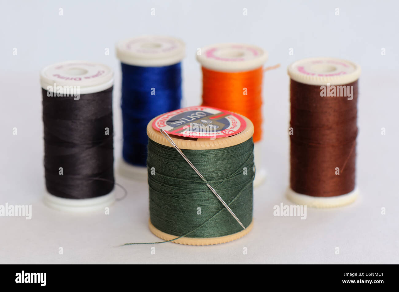 Needle and bobbins of coloured thread Stock Photo - Alamy