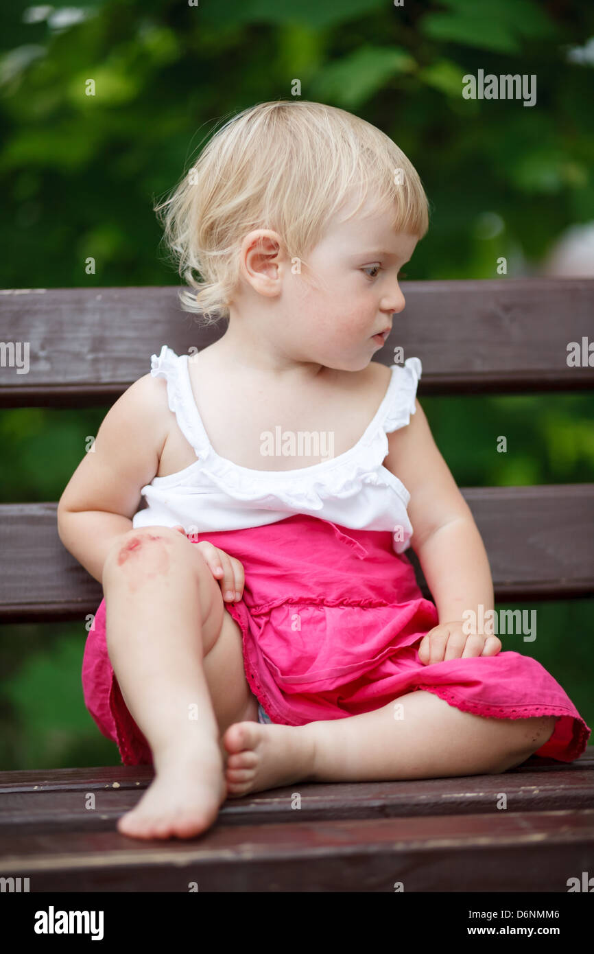 little girl sitting on park bench looking sideways Stock Photo - Alamy