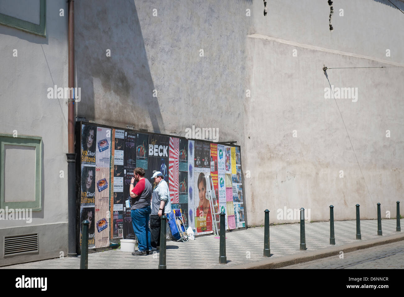 Men putting poster on a wall, Prague Stock Photo - Alamy
