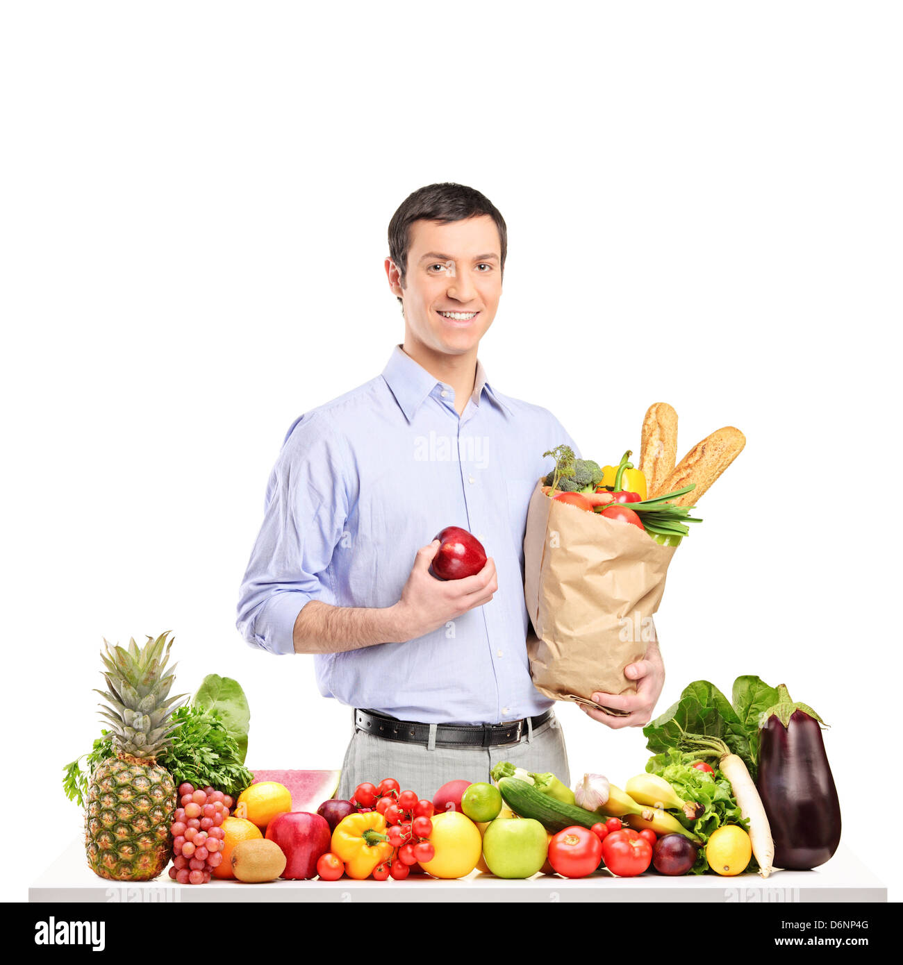 Smiling man holding an apple and paper bag with food products, posing ...