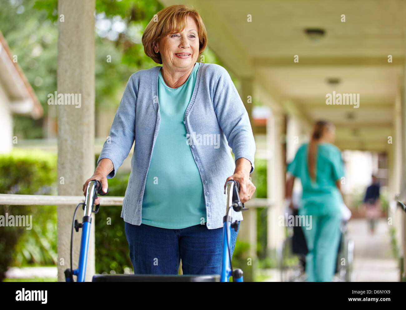 Old happy woman with walker on a stroll in the park of a nursing home ...