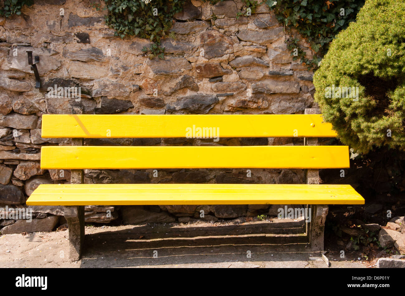 bright yellow park bench in front of a stone wall Stock Photo - Alamy