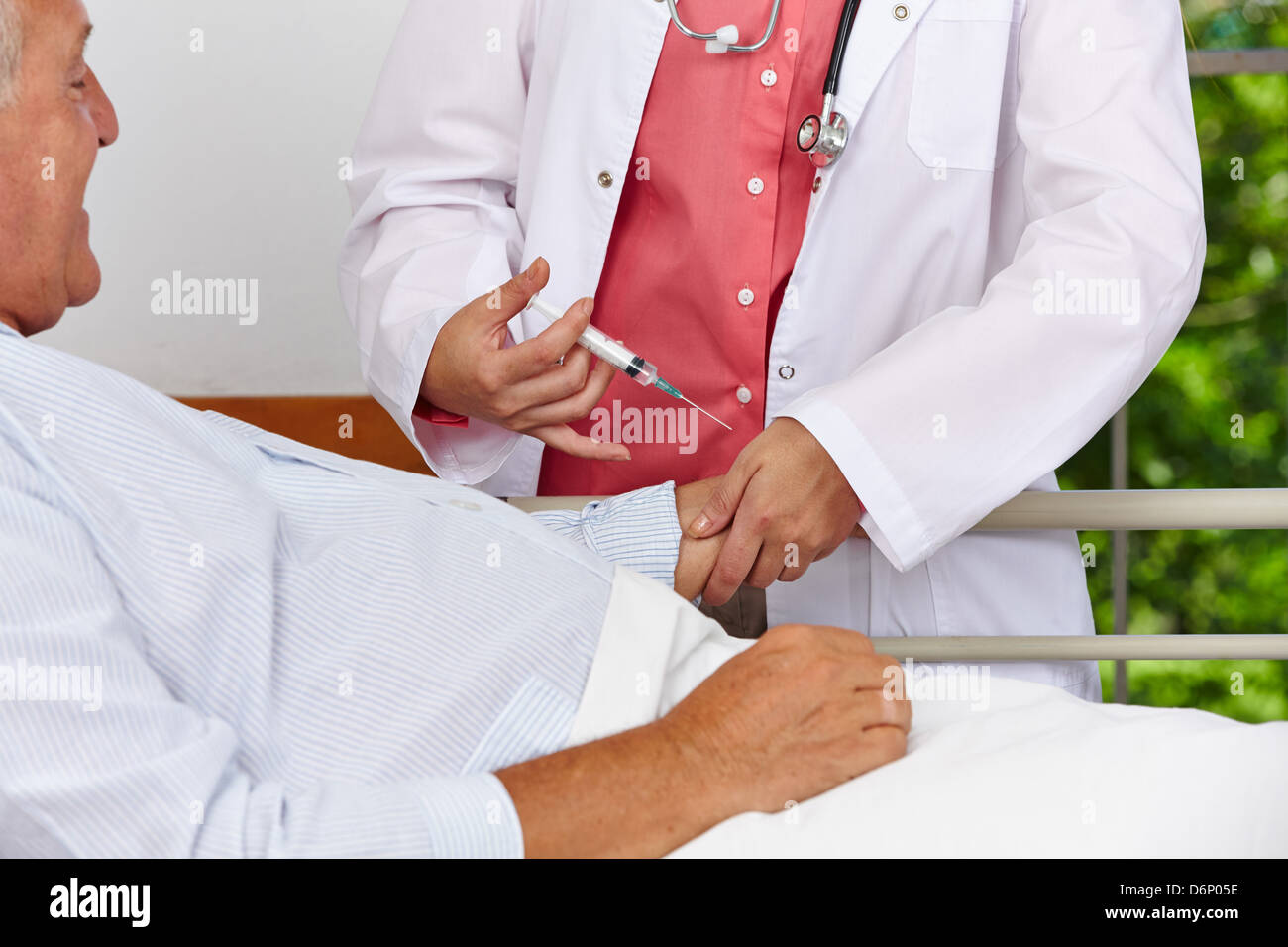 Nurse giving patient in hospital bed a syringe injection in the arm ...