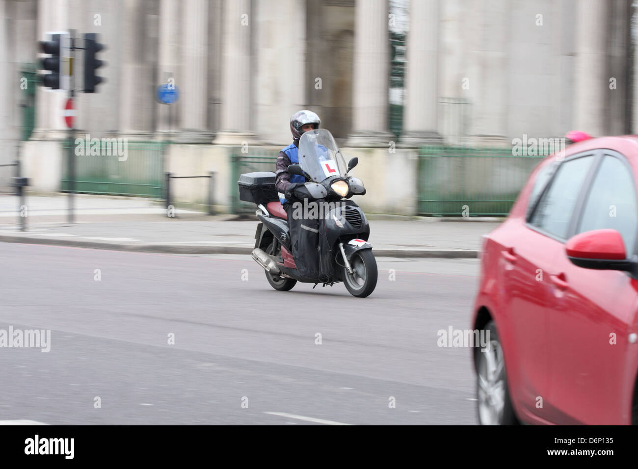 A learner motorcyclist and part of a car traveling along a road in ...