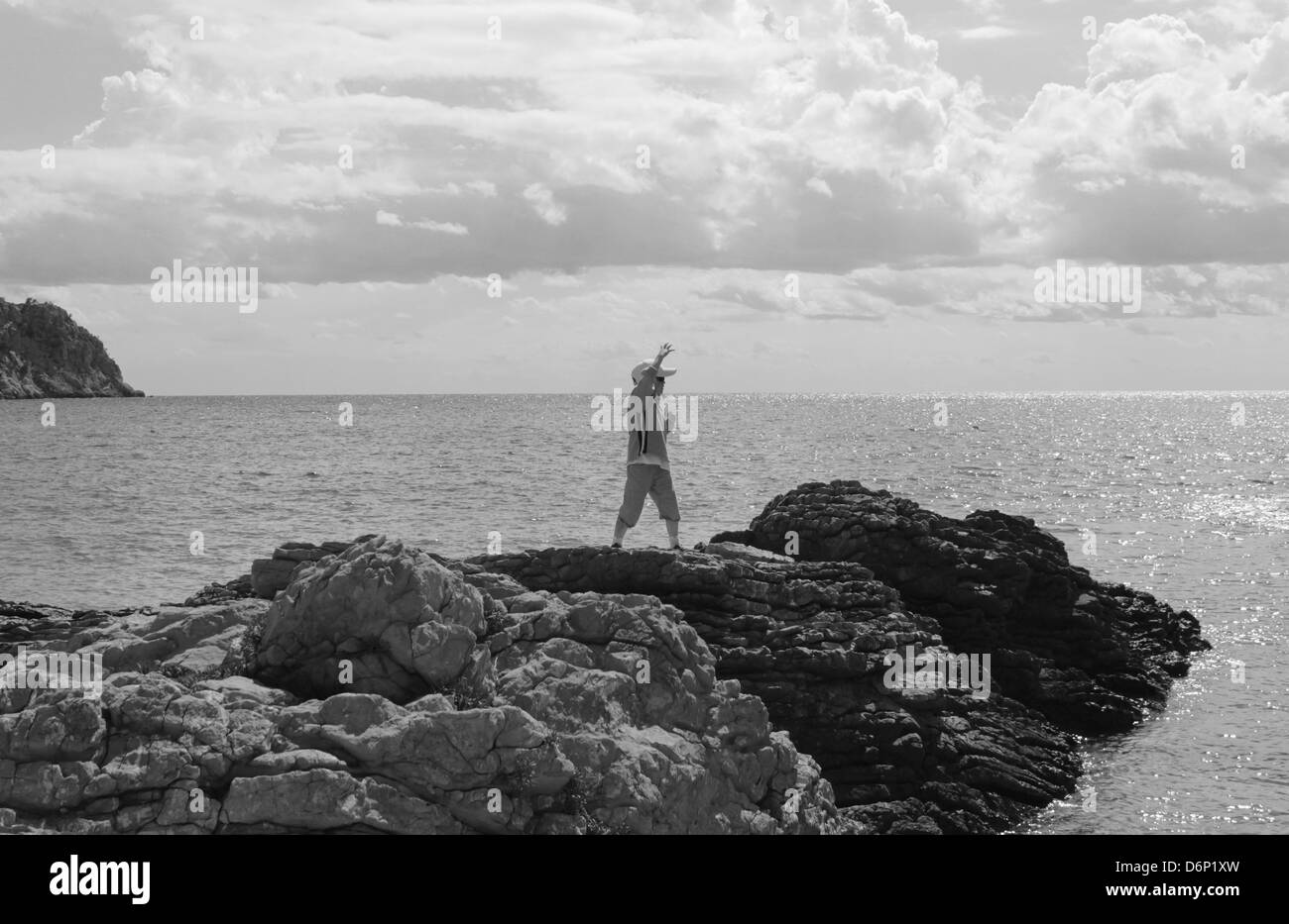 Boy throwing pebbles into the sea Stock Photo - Alamy