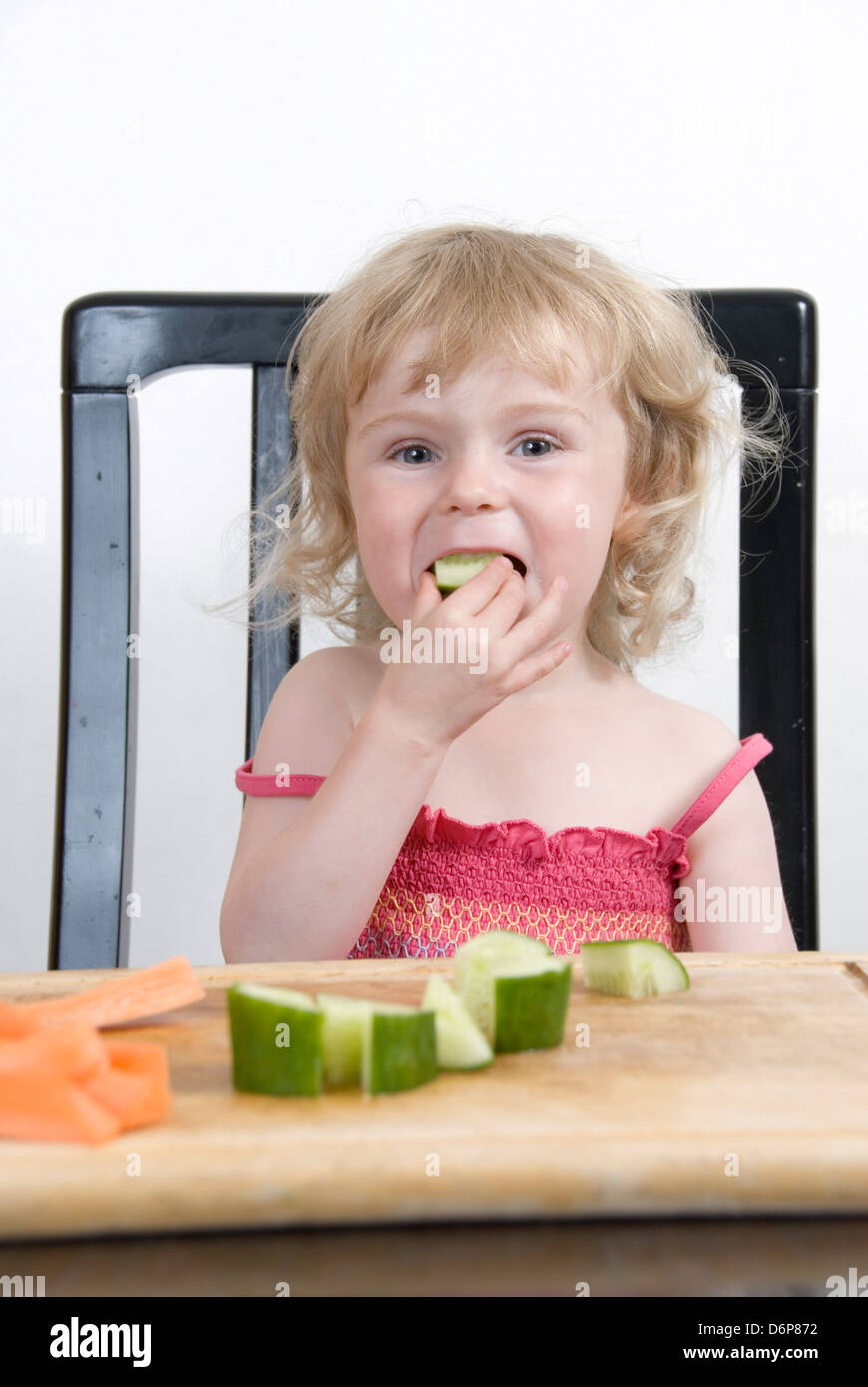 Young girl eating cucumber and other raw vegetable snack foods. Healthy ...