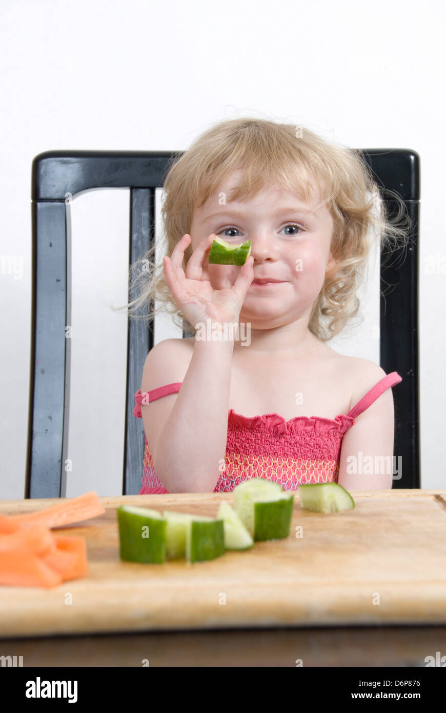 Young girl eating cucumber and other raw vegetable snack foods. Healthy ...
