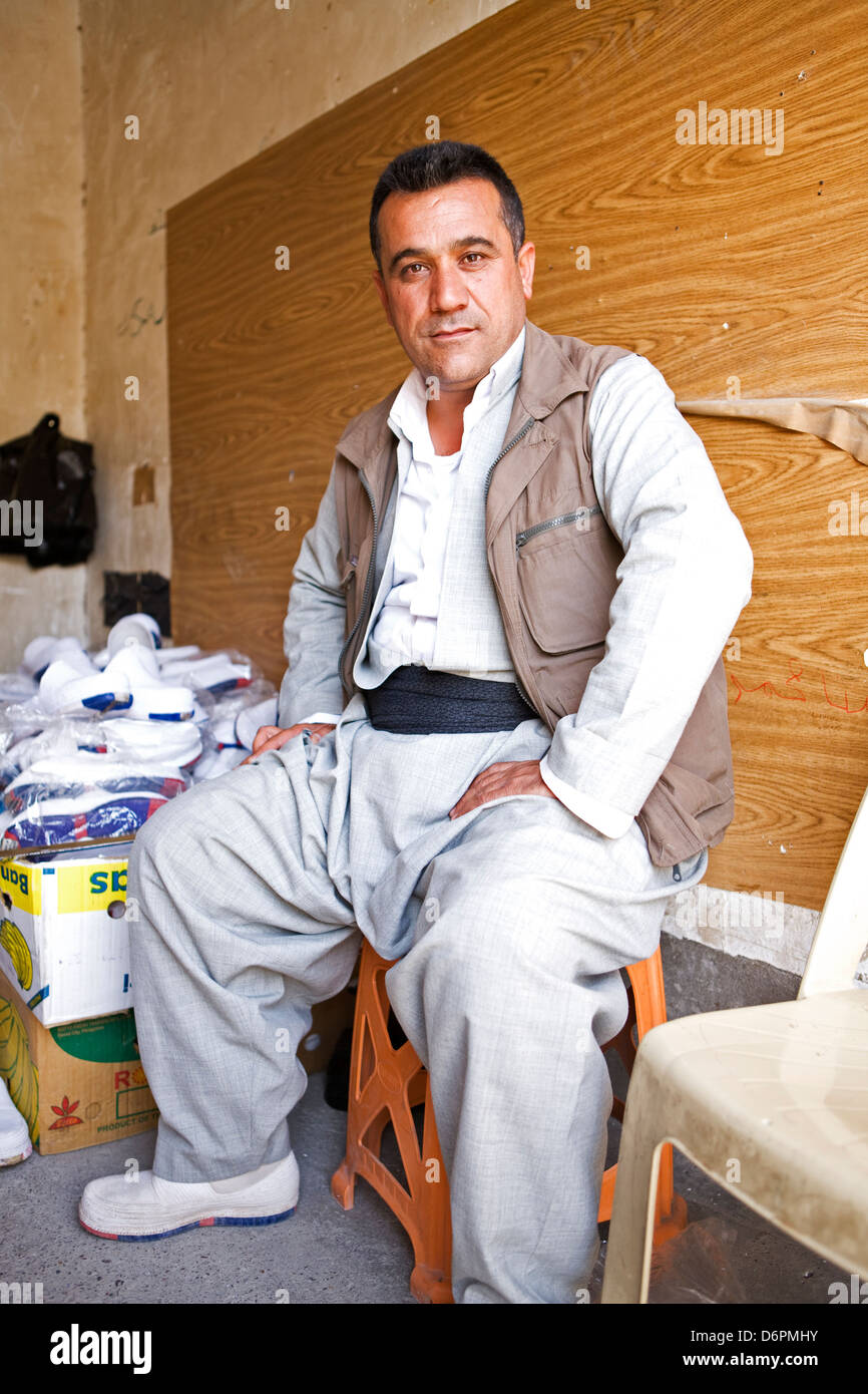 An Iraqi man in traditional clothes and shoes sitting near the Citadel ...