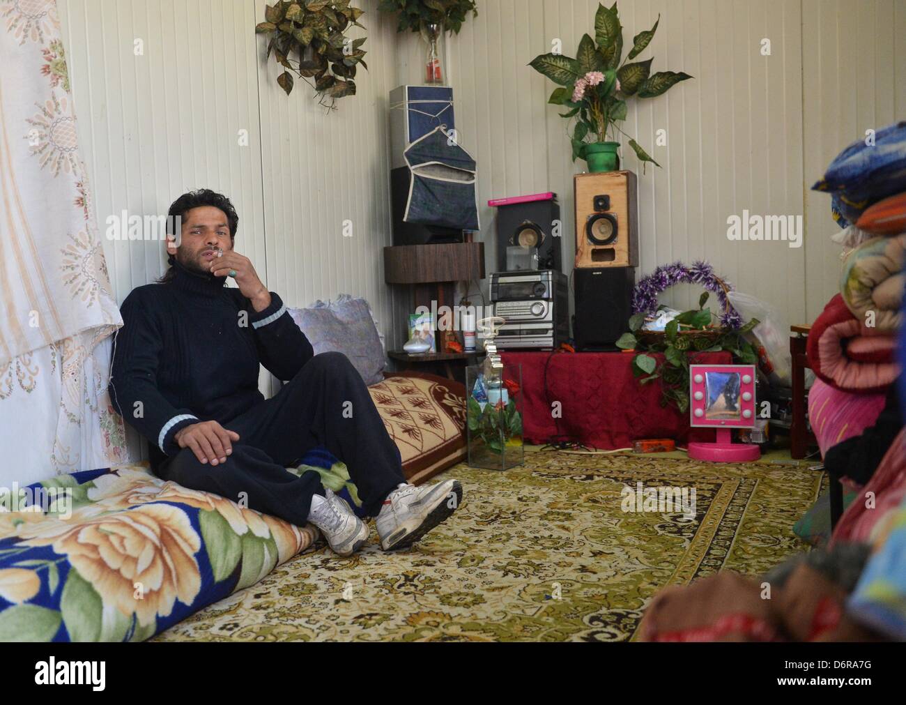 A man sits in the living room of his container house smoking a ...