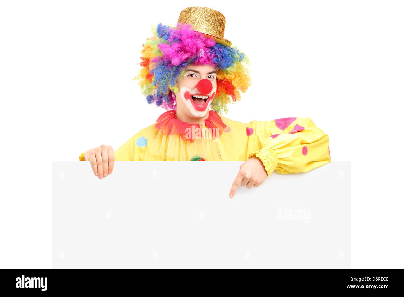 A happy male clown pointing on a blank panel isolated on white ...
