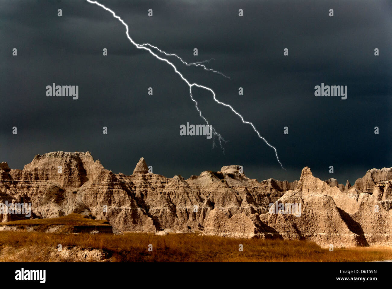 Storm clouds over eroded hills in badlands with lightning. South Dakota ...