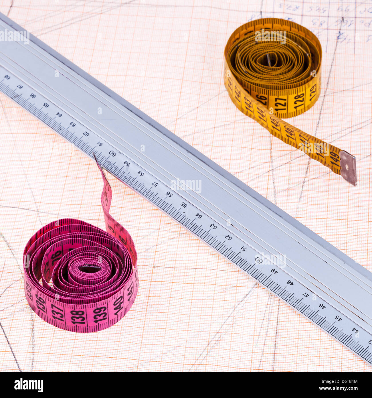 Pink and yellow measure tapes and metal ruler at graph paper Stock ...