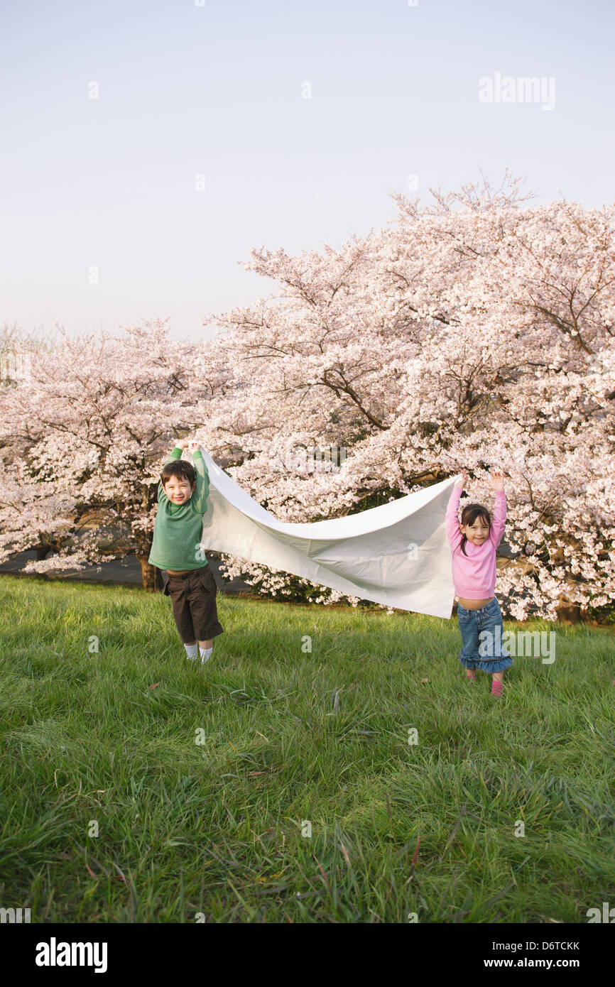 Two children with white cloth and cherry trees in the background Stock ...