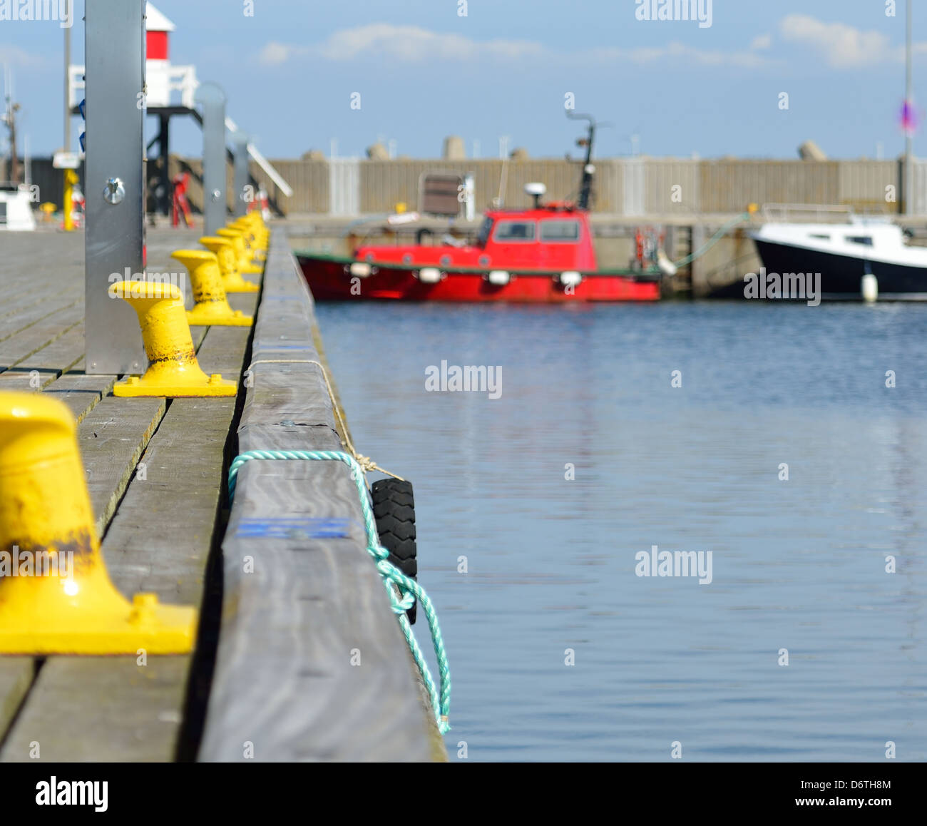 Docks with yellow bollards. A red boat in the background Stock Photo ...