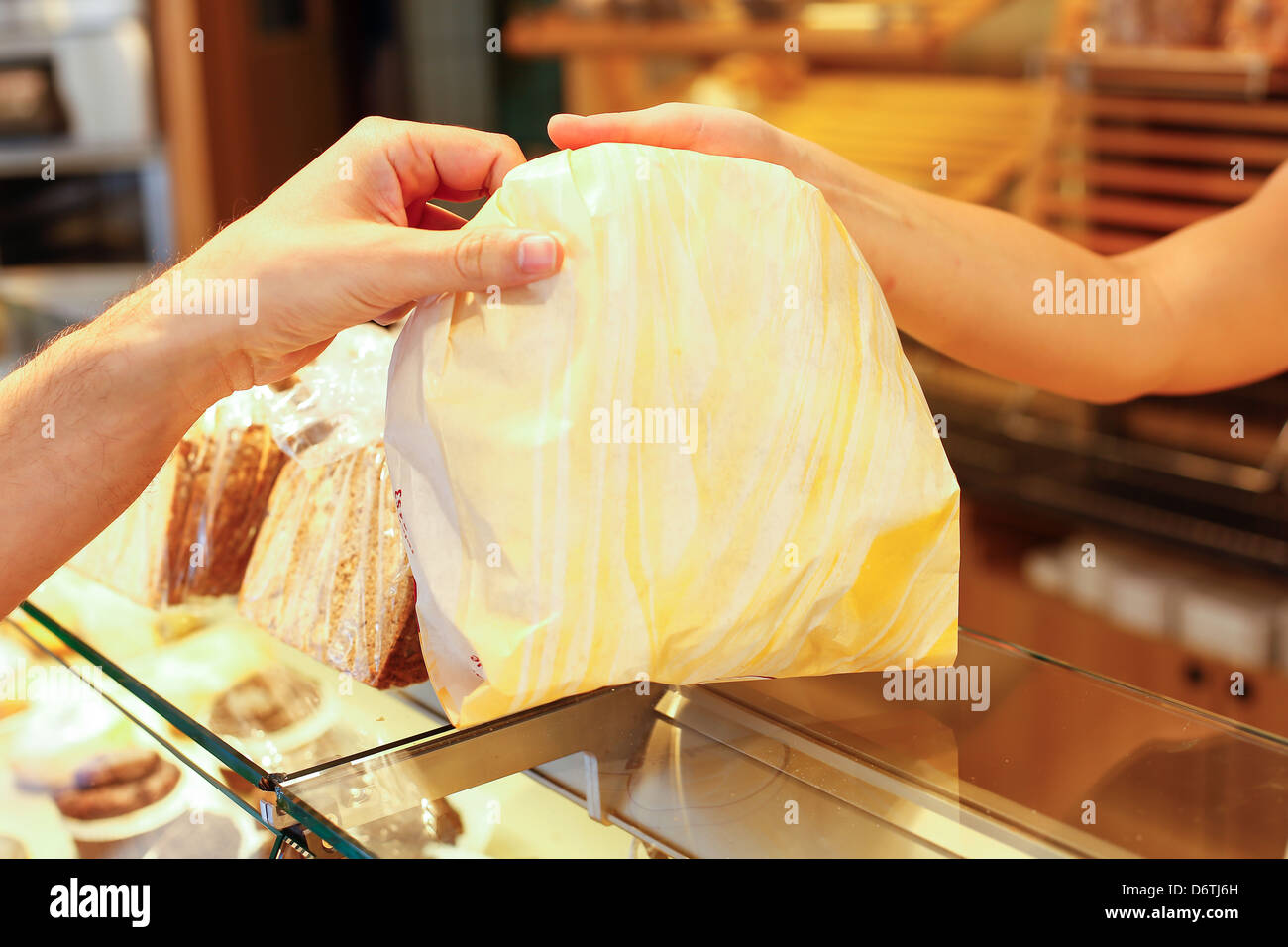 Bakery shopkeeper hands bag of bread over to customer Stock Photo - Alamy