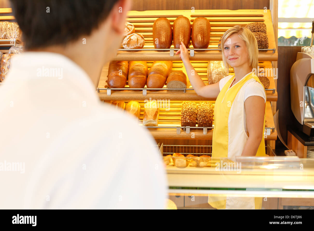 Bakery shopkeeper shows bread to customer Stock Photo - Alamy