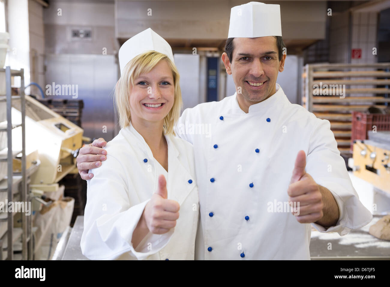 Two bakers showing thumbs up in bakery Stock Photo - Alamy