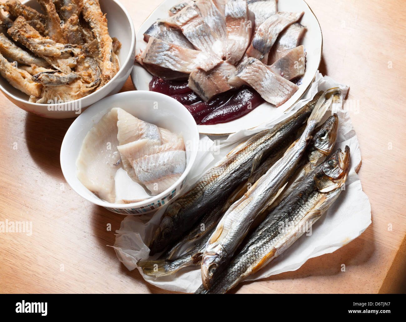 Assorted fish on wooden table. Roasted, marinated and salted smelt fish ...