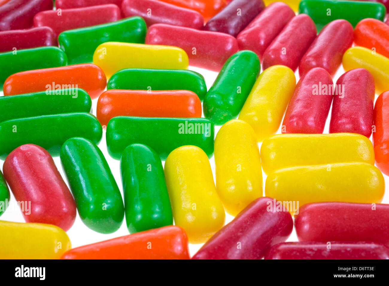 Several pieces of fruit flavored chewing gum atop a white background ...