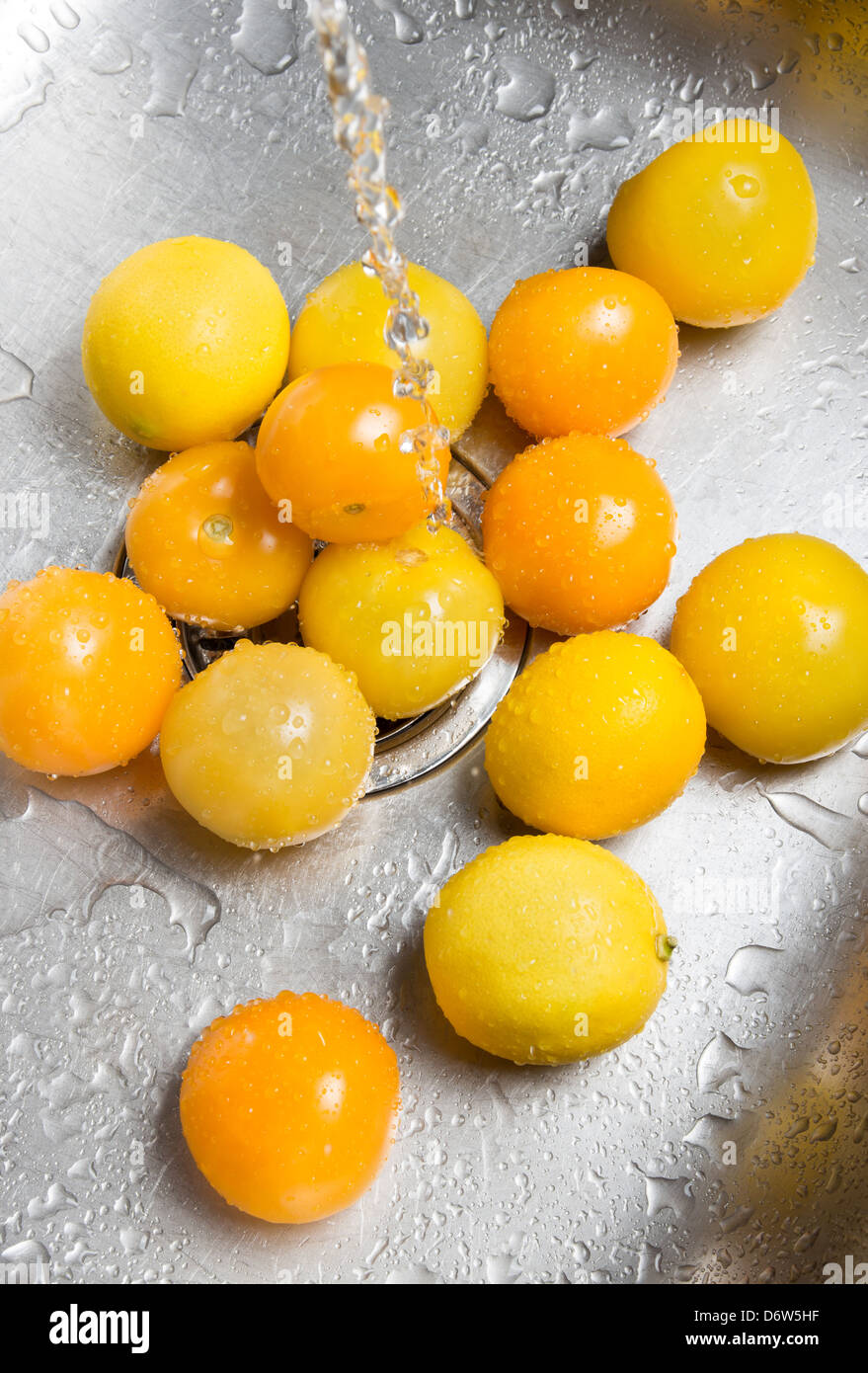 Washing yellow tomatoes and lemons in the kitchen sink Stock Photo - Alamy