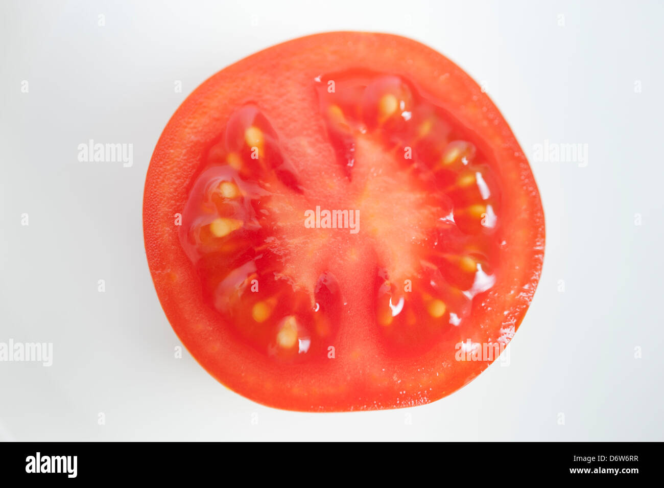 A tomato sliced in half on a white plain background Stock Photo - Alamy