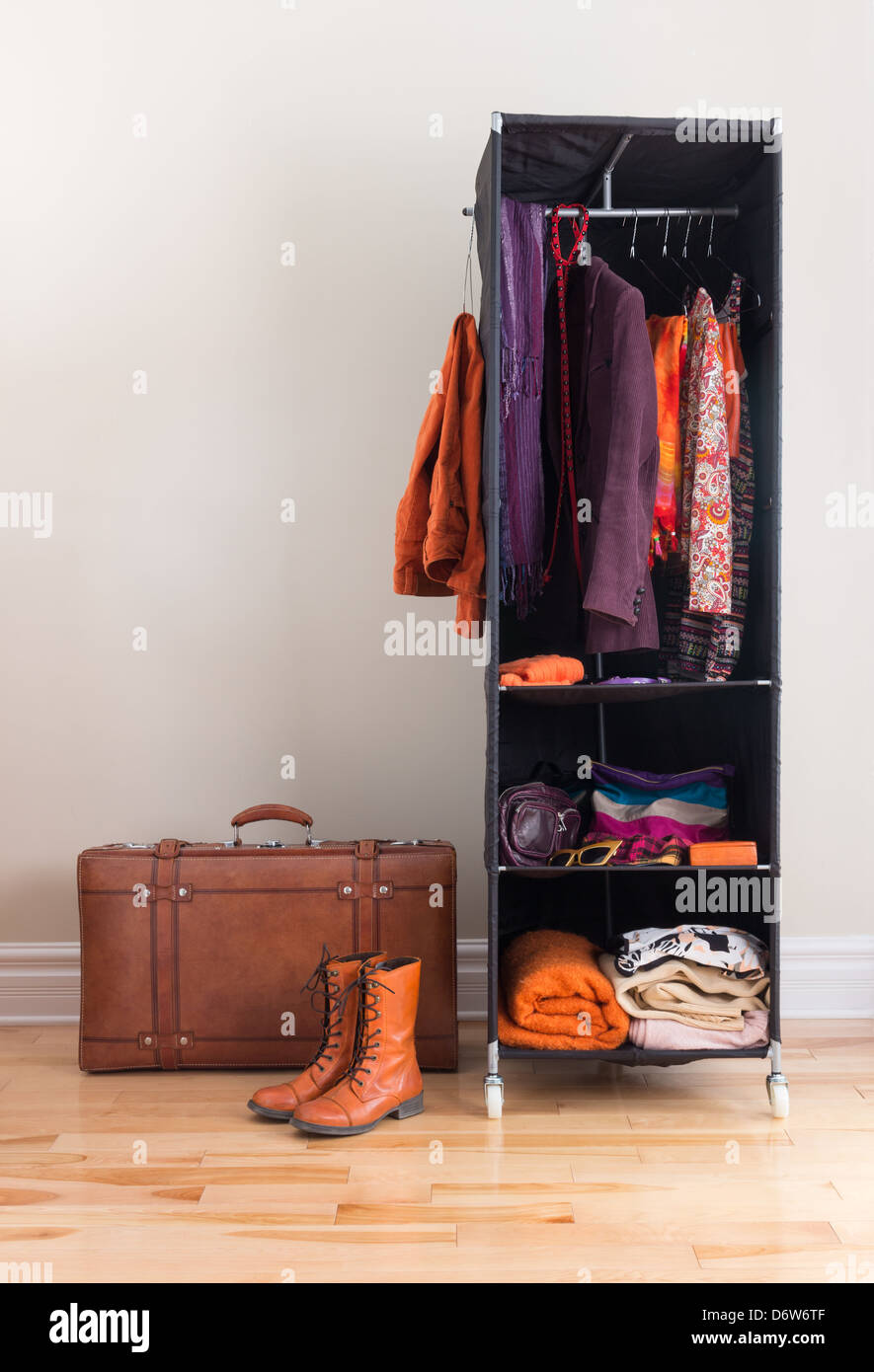 Mobile wardrobe with orange and purple clothing, and leather suitcase ...