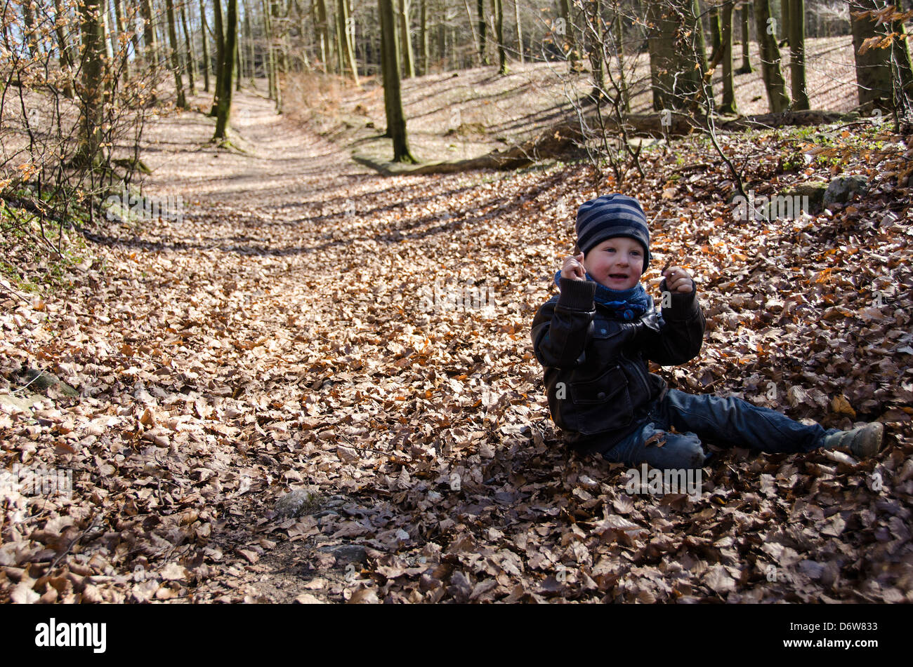 Young boy on forest floor in spring playing with leaves Stock Photo - Alamy