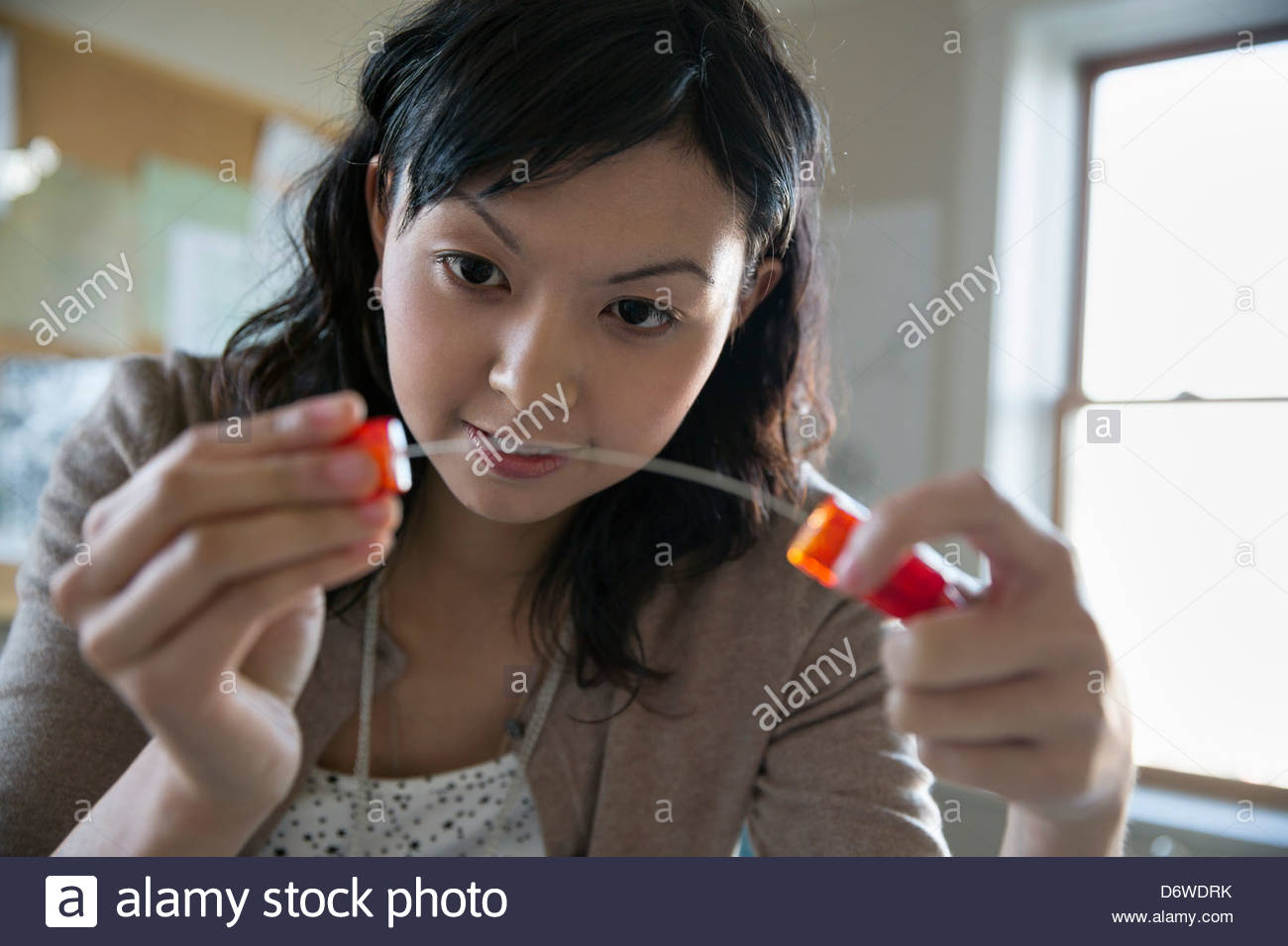 Young woman threading beads onto string at work Stock Photo - Alamy