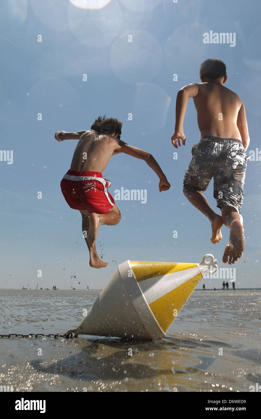 St. Peter-Ording, Germany, two kids jumping on the beach at low tide √ ...