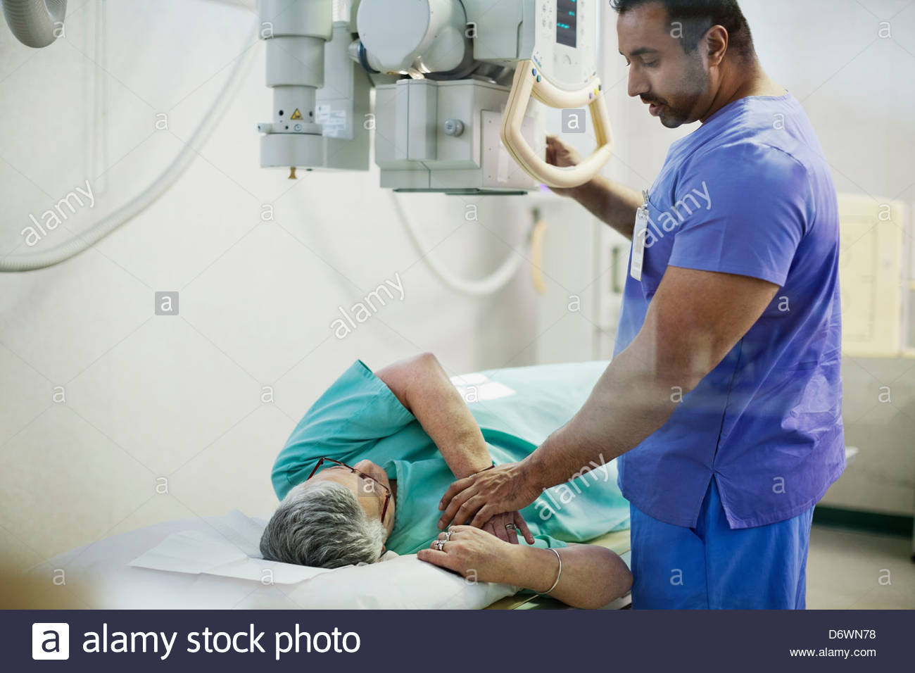 Male radiologist adjusting X-ray machine over patient in clinic Stock ...
