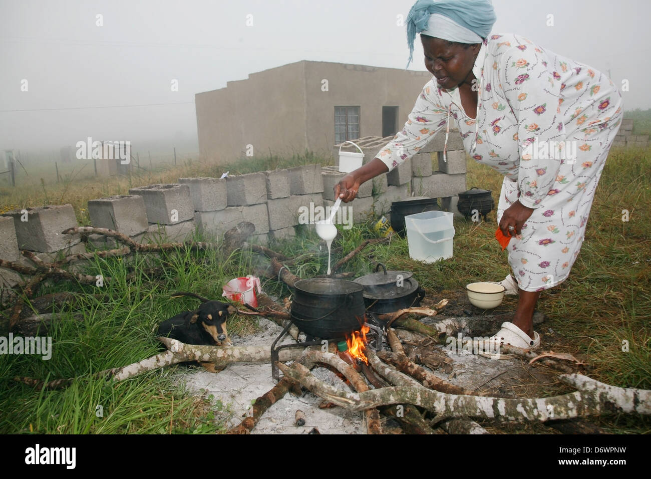 An African woman cooks outside on a wood fire as the mist rolls in ...