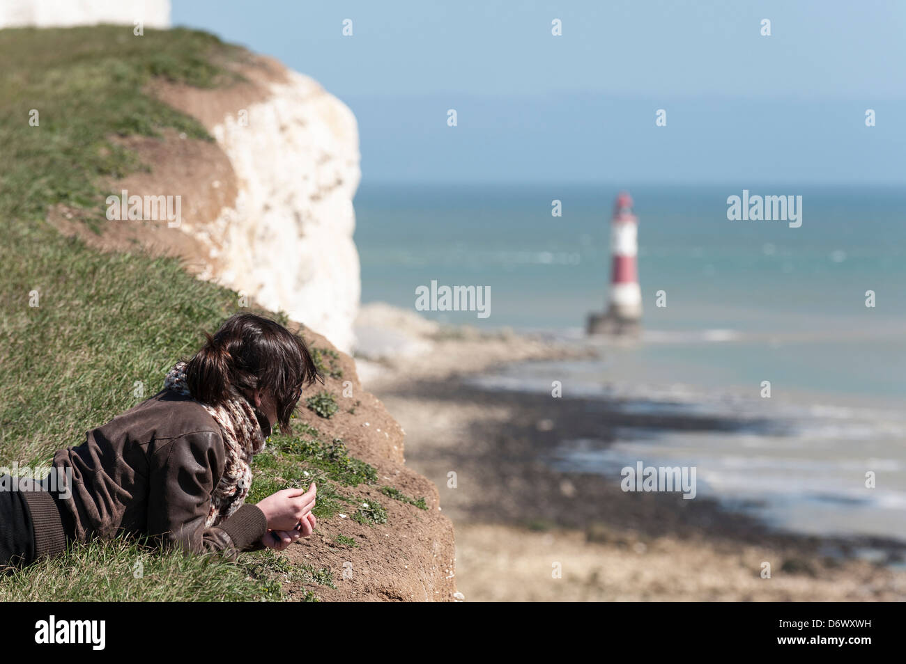 A woman lying down on a cliff overlooking Beachy Head Lighthouse Stock ...