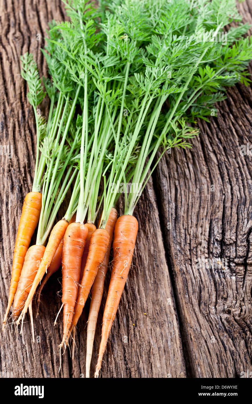 Carrots with leaves on a old wooden table Stock Photo - Alamy