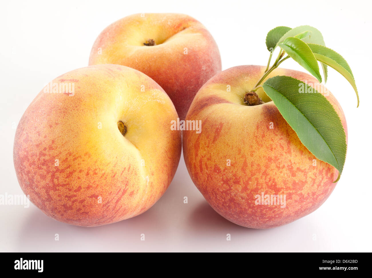 Three ripe peach with leaves on white background Stock Photo - Alamy