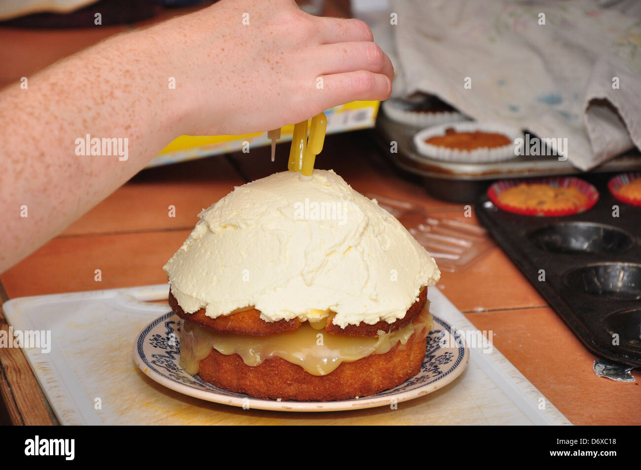 Putting the finishing touches to a small birthday cake Stock Photo - Alamy