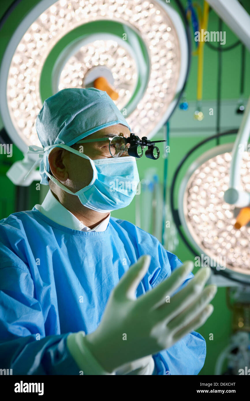 a surgeon wearing a medical loop glasses wearing examination gloves ...