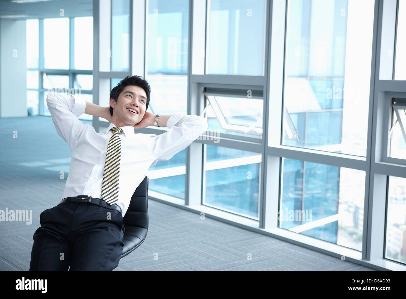 a businessman smiling while leaning back on a chair Stock Photo - Alamy