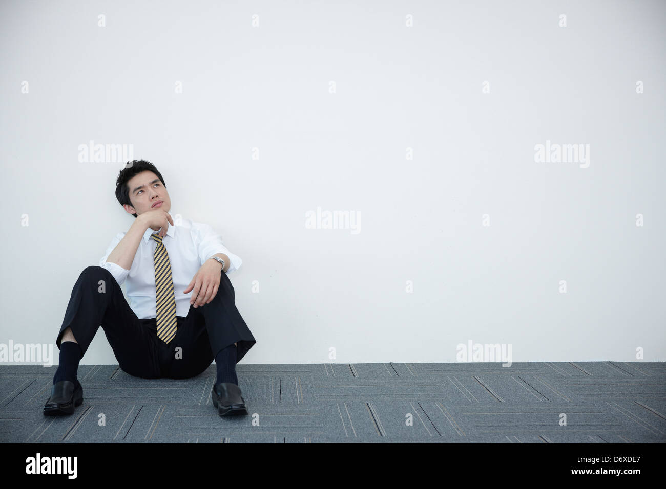 a distressed businessman sitting against wall Stock Photo - Alamy