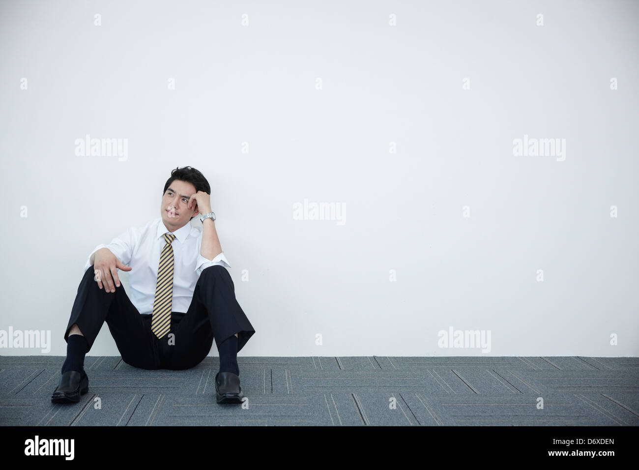 a distressed businessman sitting against wall Stock Photo - Alamy