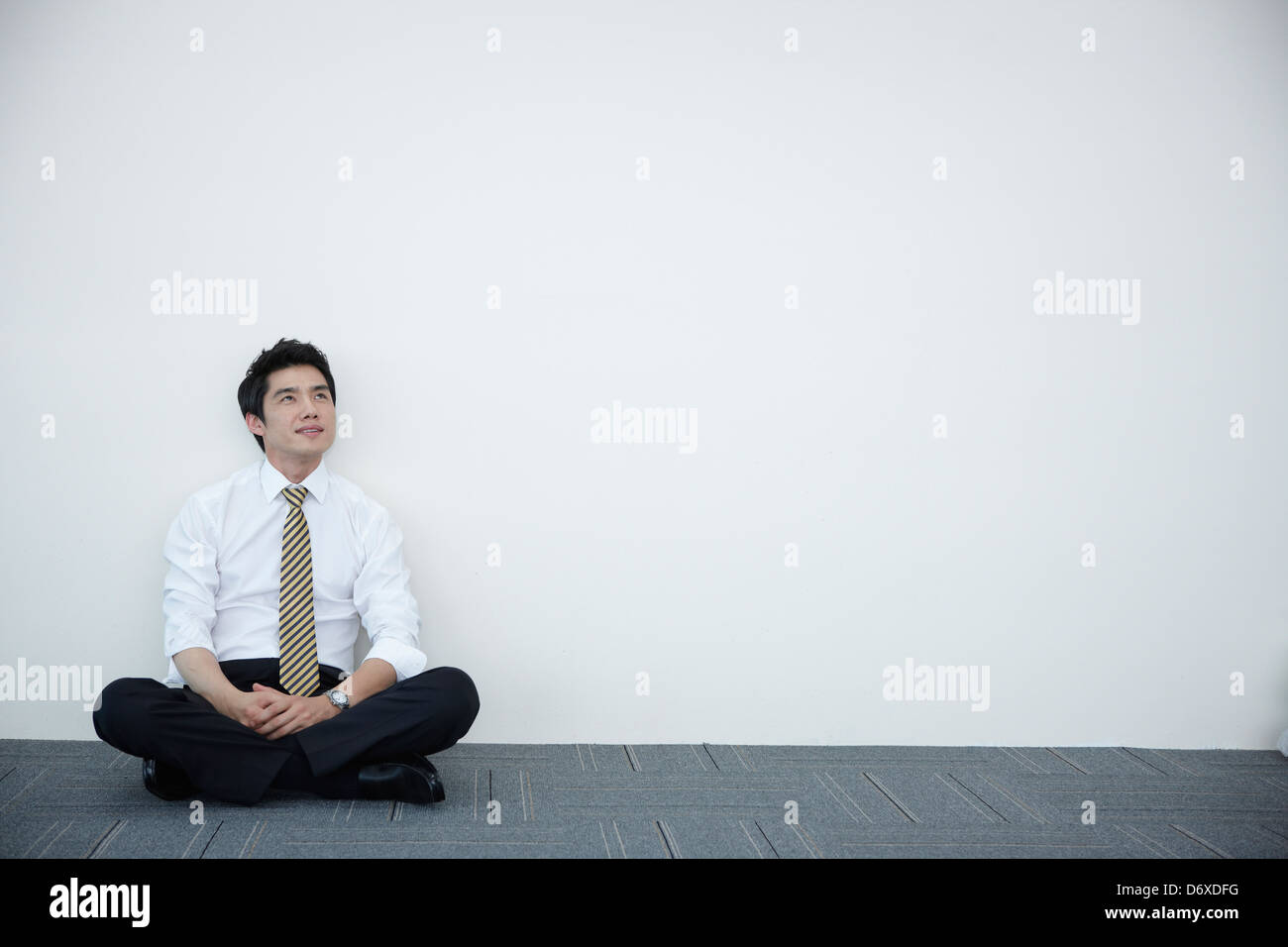 a businessman sitting against wall Stock Photo - Alamy