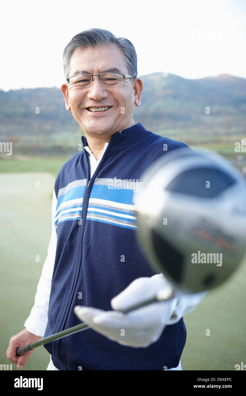 a man holding a golf club at a golf course Stock Photo - Alamy