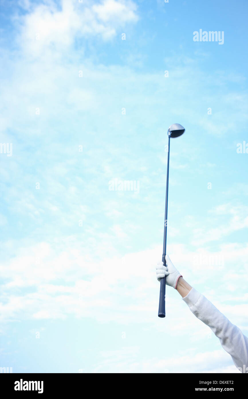 a hand holding a golf club under blue sky Stock Photo - Alamy