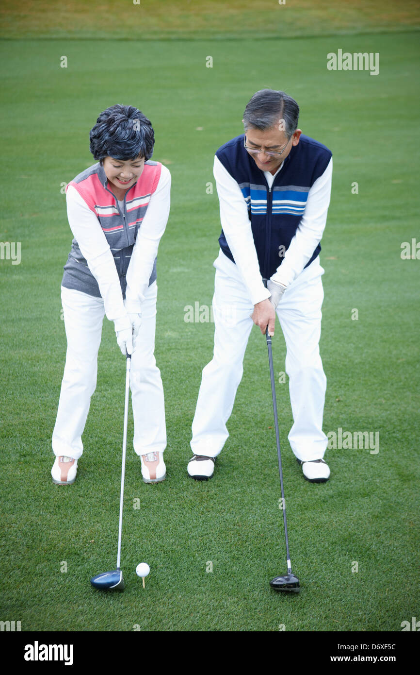 a couple at a golf course standing in golf swing pose Stock Photo - Alamy