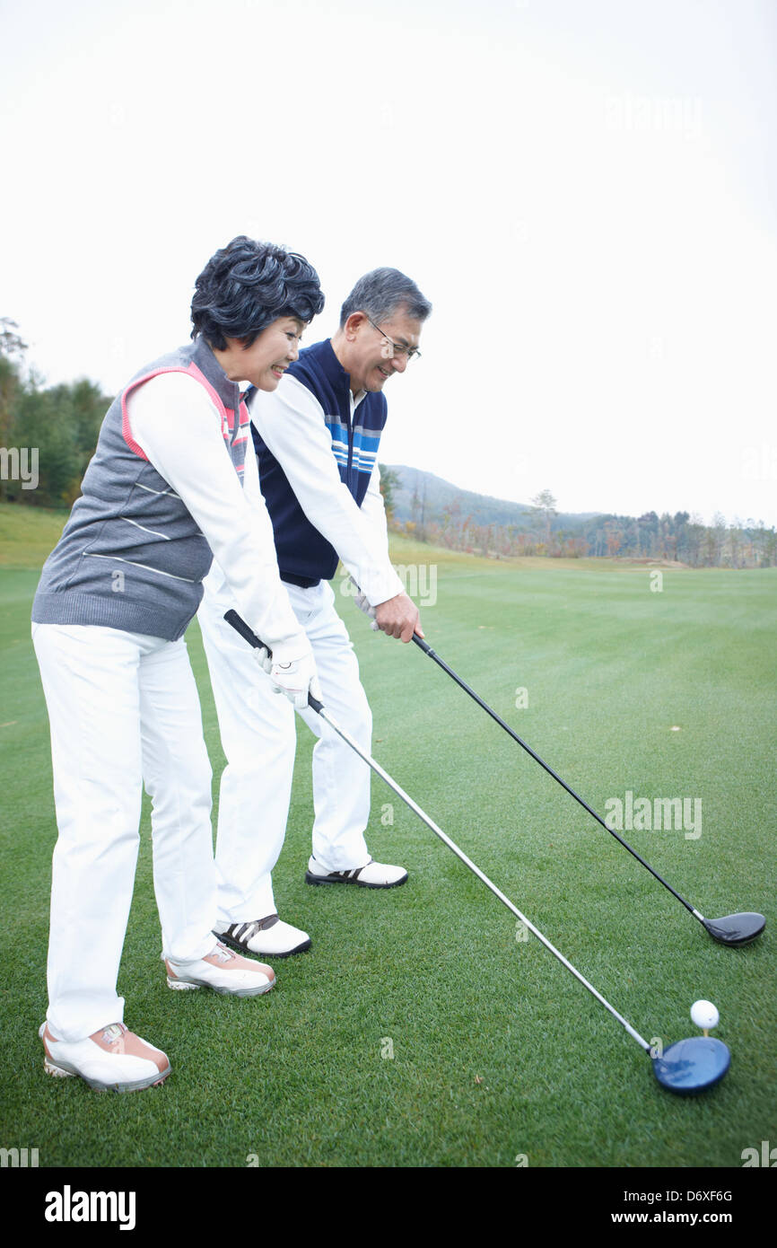 a couple at a golf course standing in golf swing pose Stock Photo - Alamy