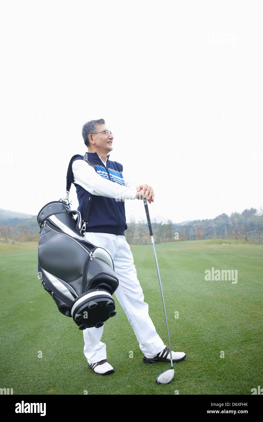 a man standing with a golf bag at a golf course Stock Photo - Alamy