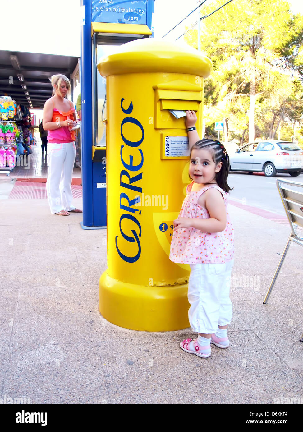 A young girl posts a letter in a yellow Spanish post box Stock Photo ...