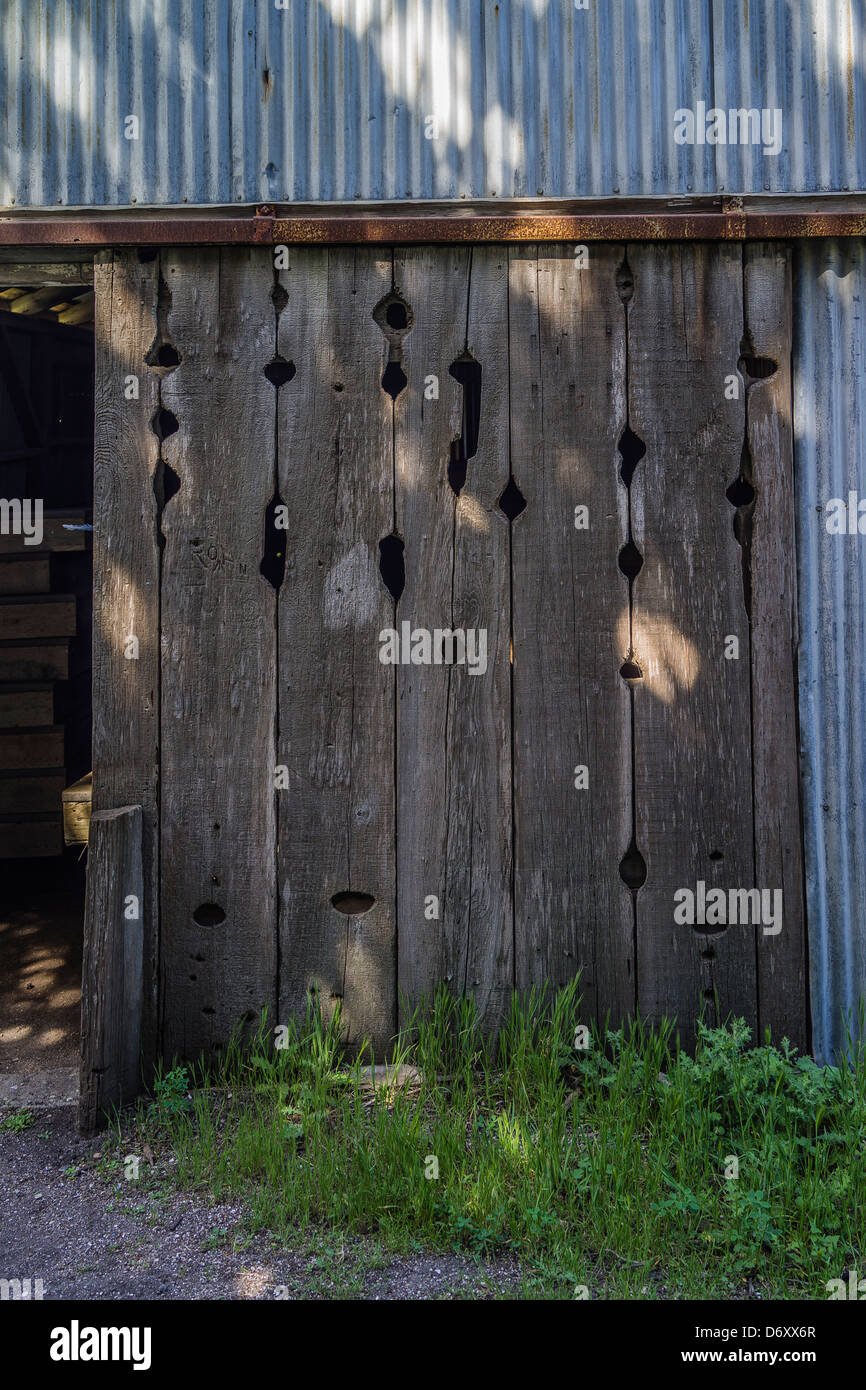A detail of a well worn wooden barn door with unusual shaped holes in ...